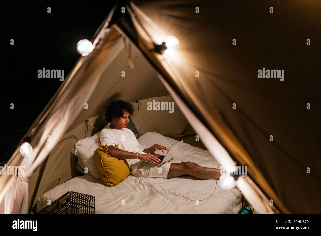 latin man working on computer in tent bed Stock Photo - Alamy