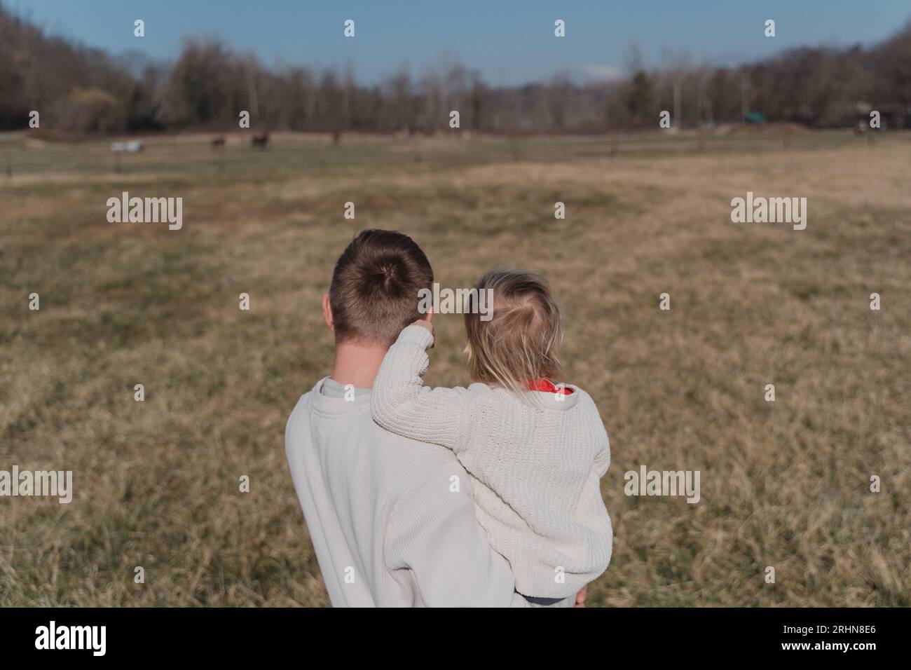 A man tightly hugs a small child in a dry field, back view Stock Photo ...