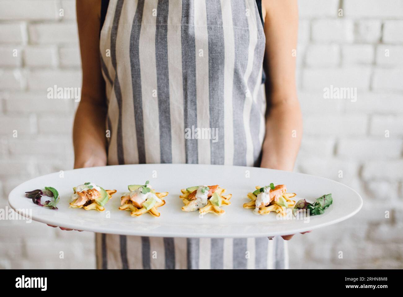 Server in apron holding tray of hors d'oeuvres Stock Photo - Alamy