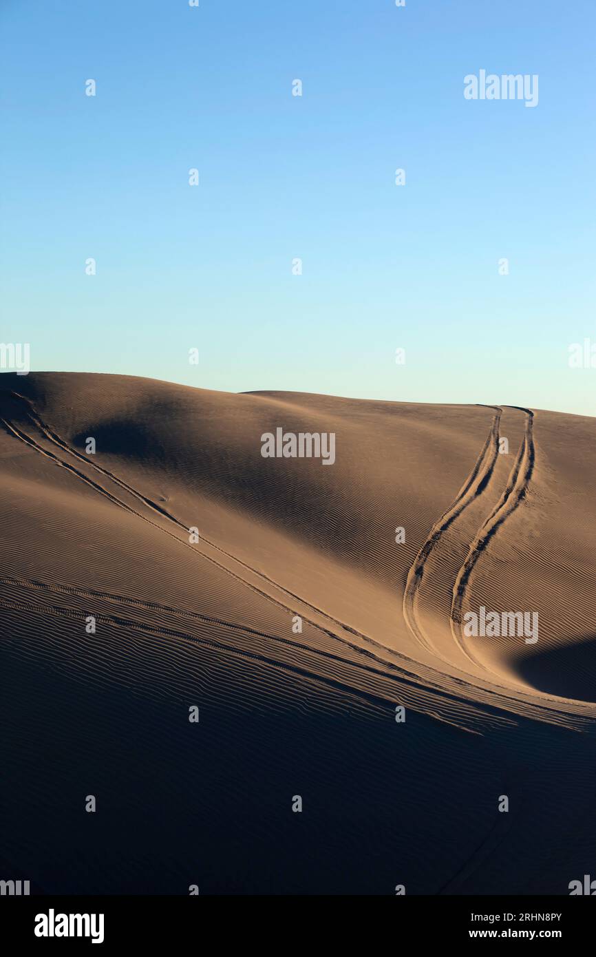Rolling sand dunes with wheel ruts and shadow vertical Stock Photo - Alamy