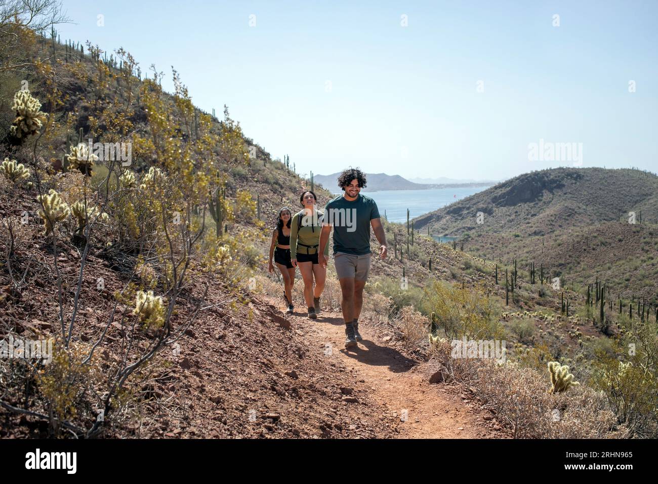 Hikers walking hilly path lake in background Stock Photo - Alamy