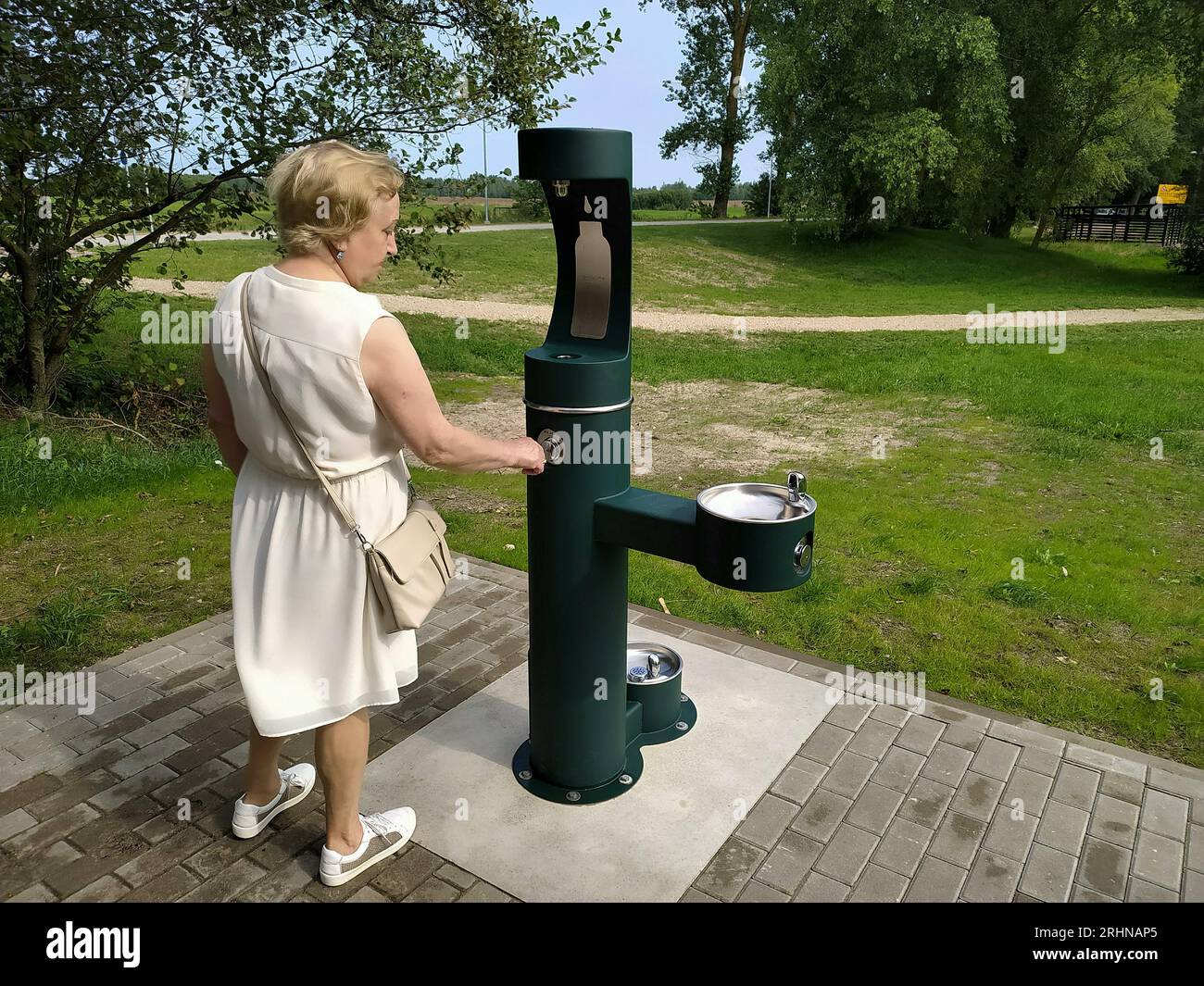 A new column with drinking water in Riga's Daugavgriva district. Woman ...