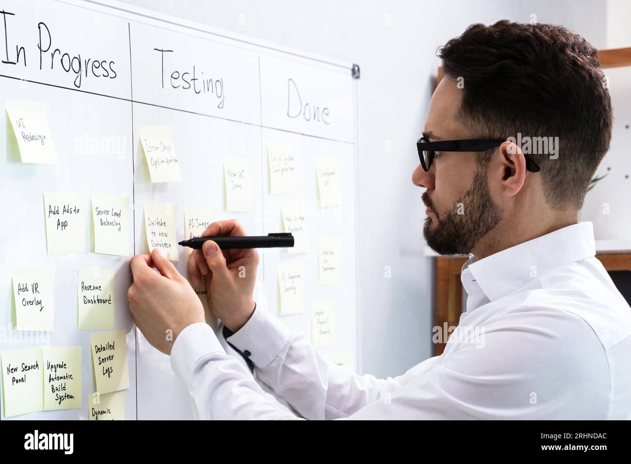 Side View Of Businessman Writing On Sticky Notes Attached To White ...