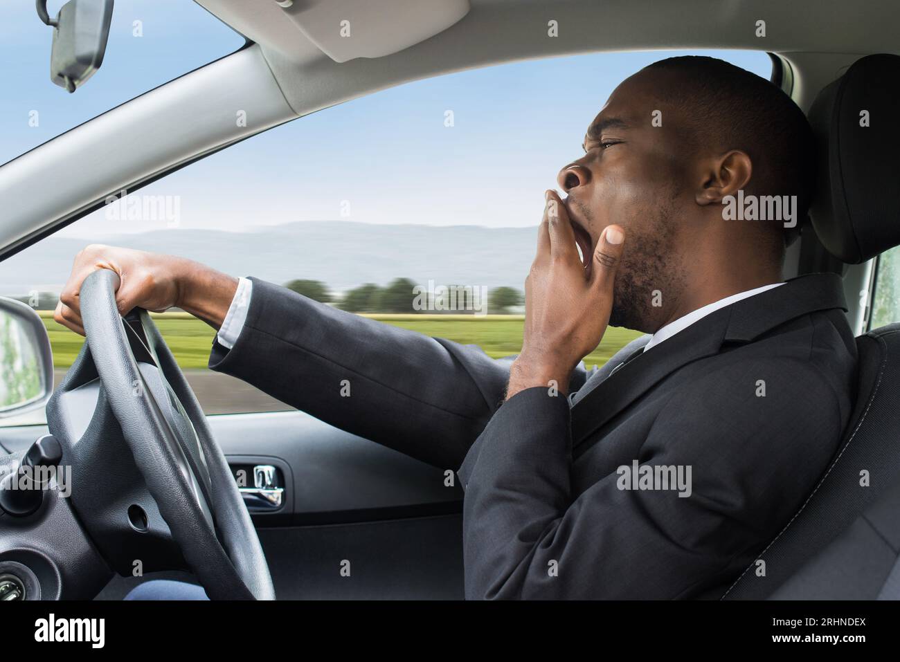 Side View Of A Young African Businessman Yawning While Driving Car ...