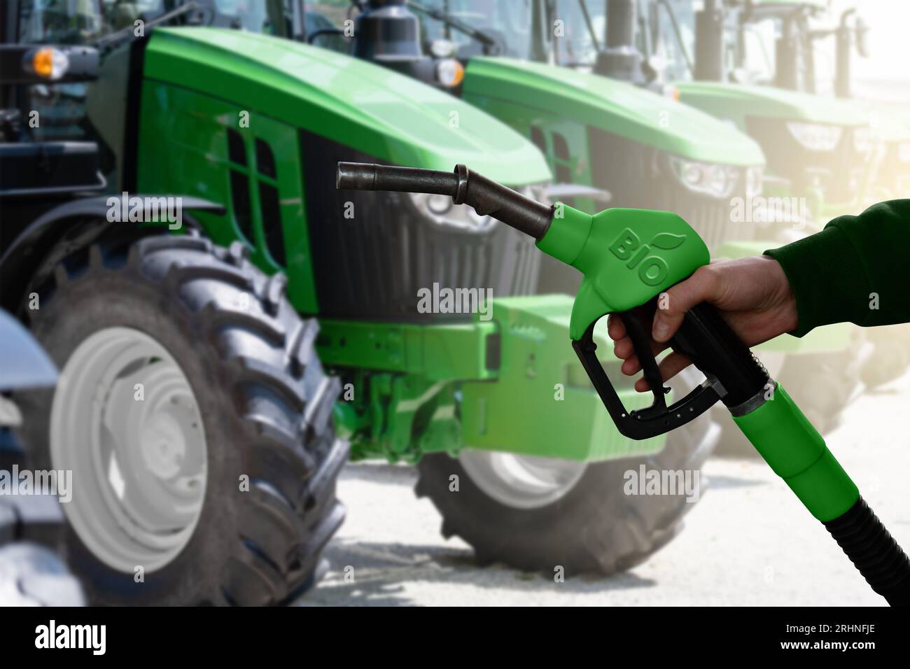 Hand with biofuel refueling nozzle on a background of agricultural ...