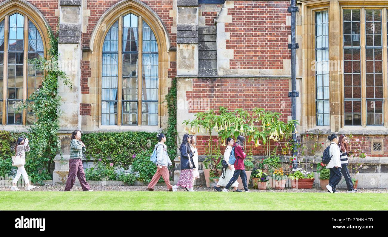 A group of tourists walk past the dining hall at Pembroke College ...
