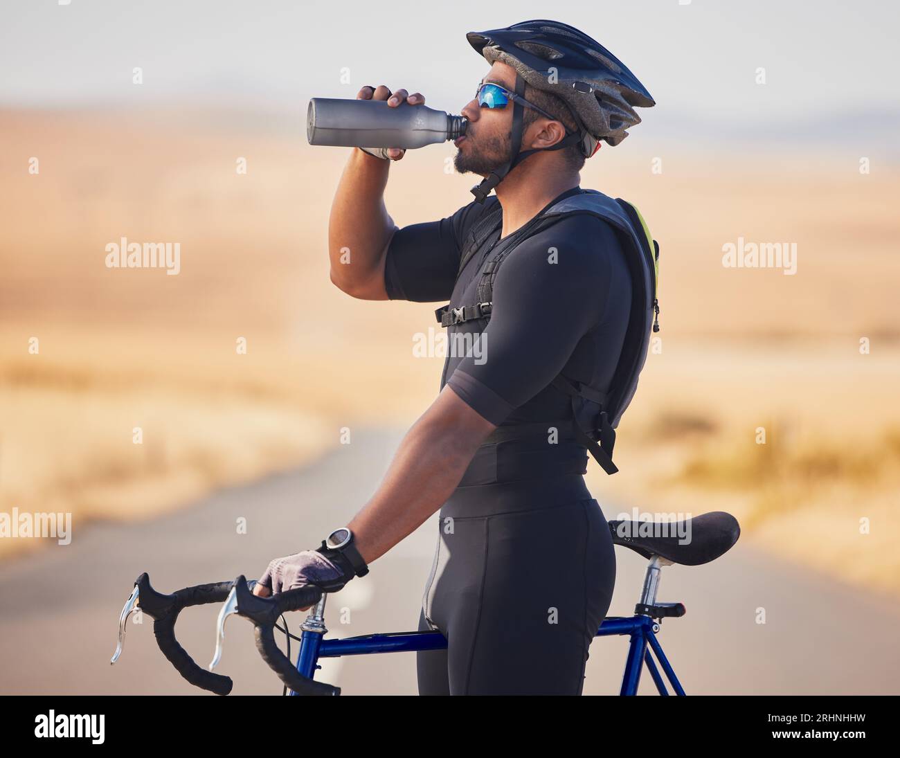 Fitness, nature and man cyclist drinking water at race, marathon or ...