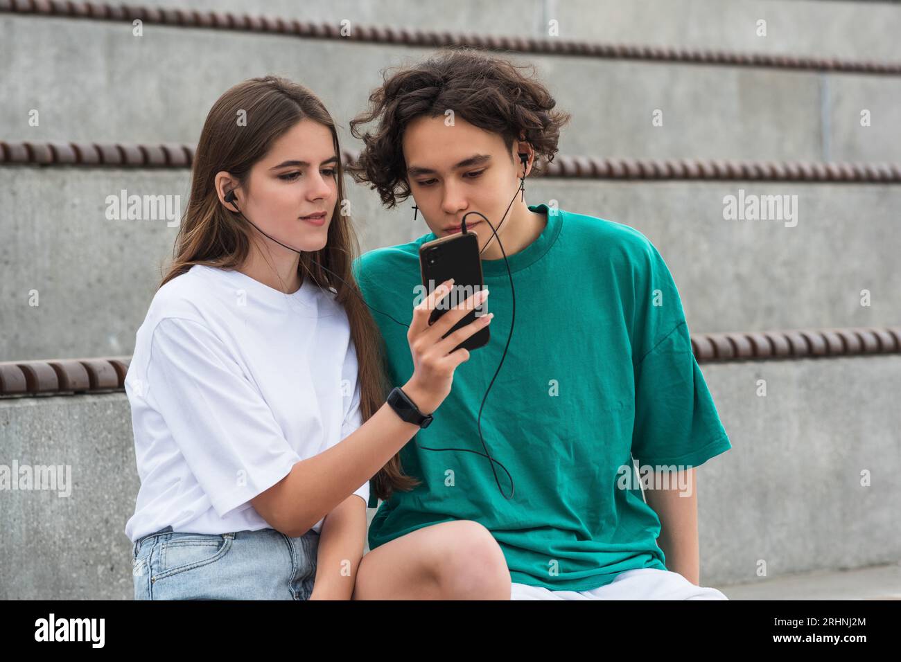 young couple together listening to the same music through headphones ...