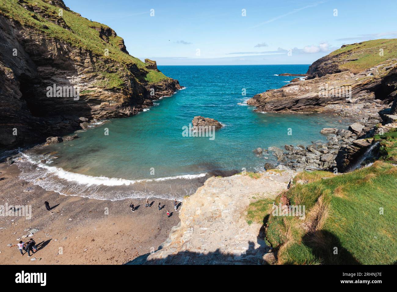 People enjoy a small sandy bay near Merlins Cave and Tinagel in ...