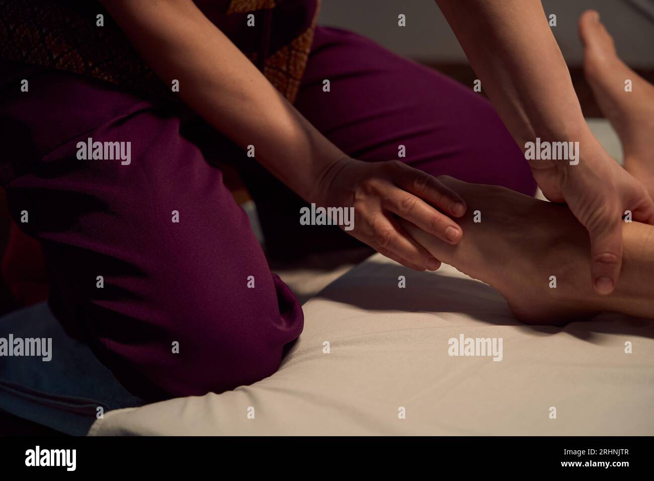 Experienced massotherapist is doing Thai feet massage to spa customer ...