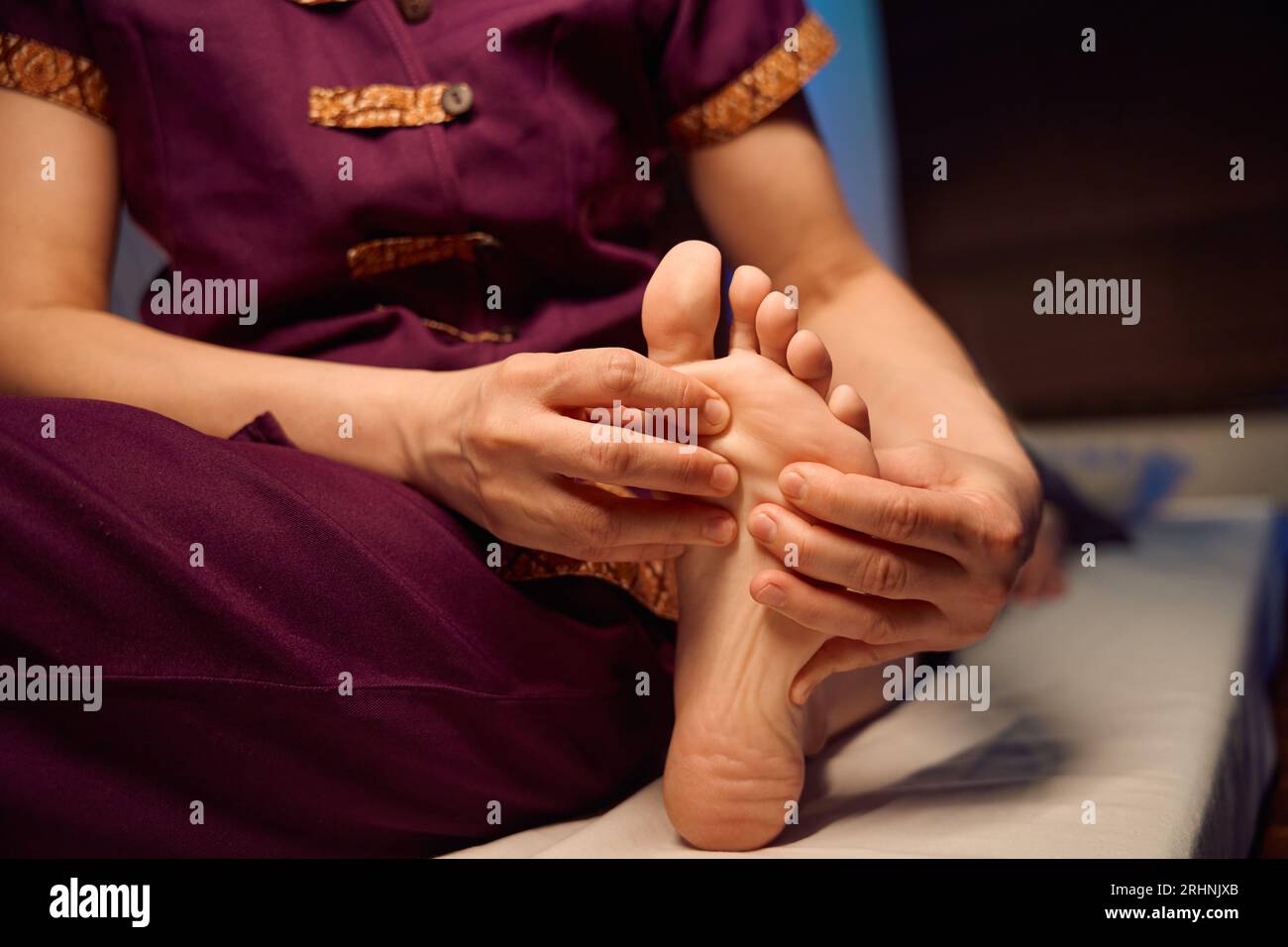Qualified massotherapist giving Thai foot massage to female client ...