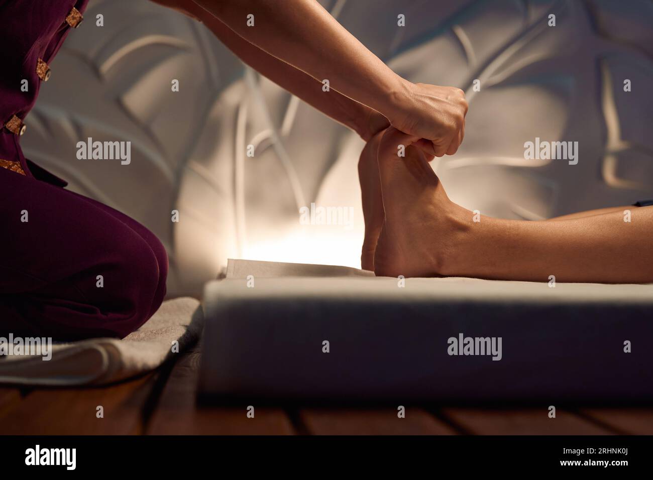 Experienced massotherapist giving traditional Thai foot massage to spa ...