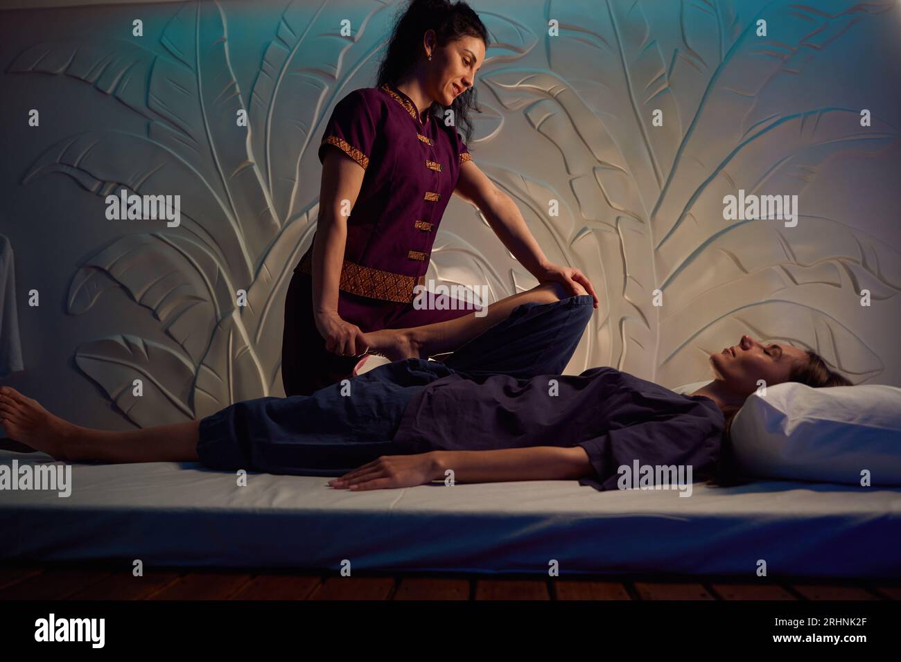 Professional massotherapist stretching lower limb muscles of young ...