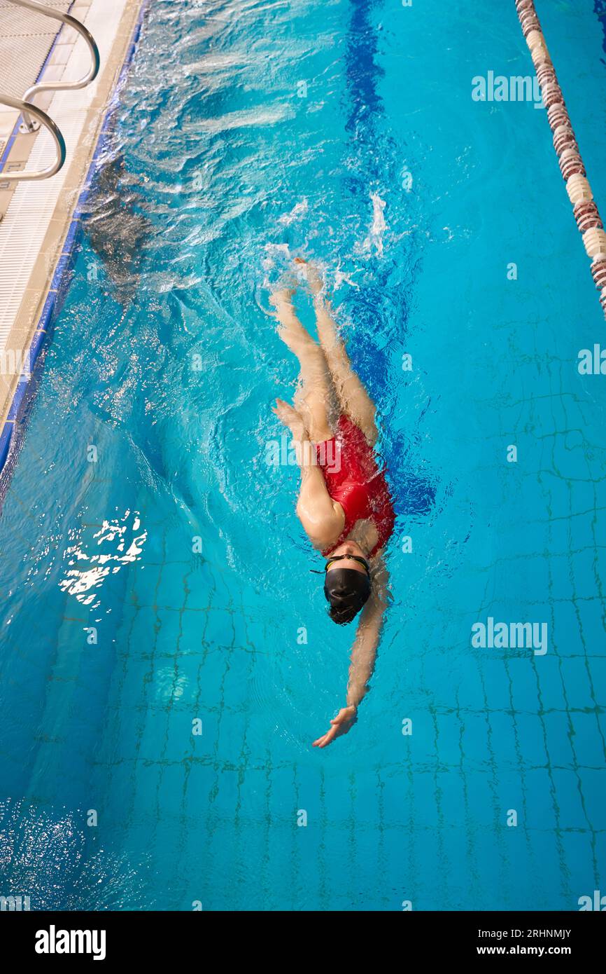 Female swimmer in swimsuit swimming on her back in pool Stock Photo - Alamy