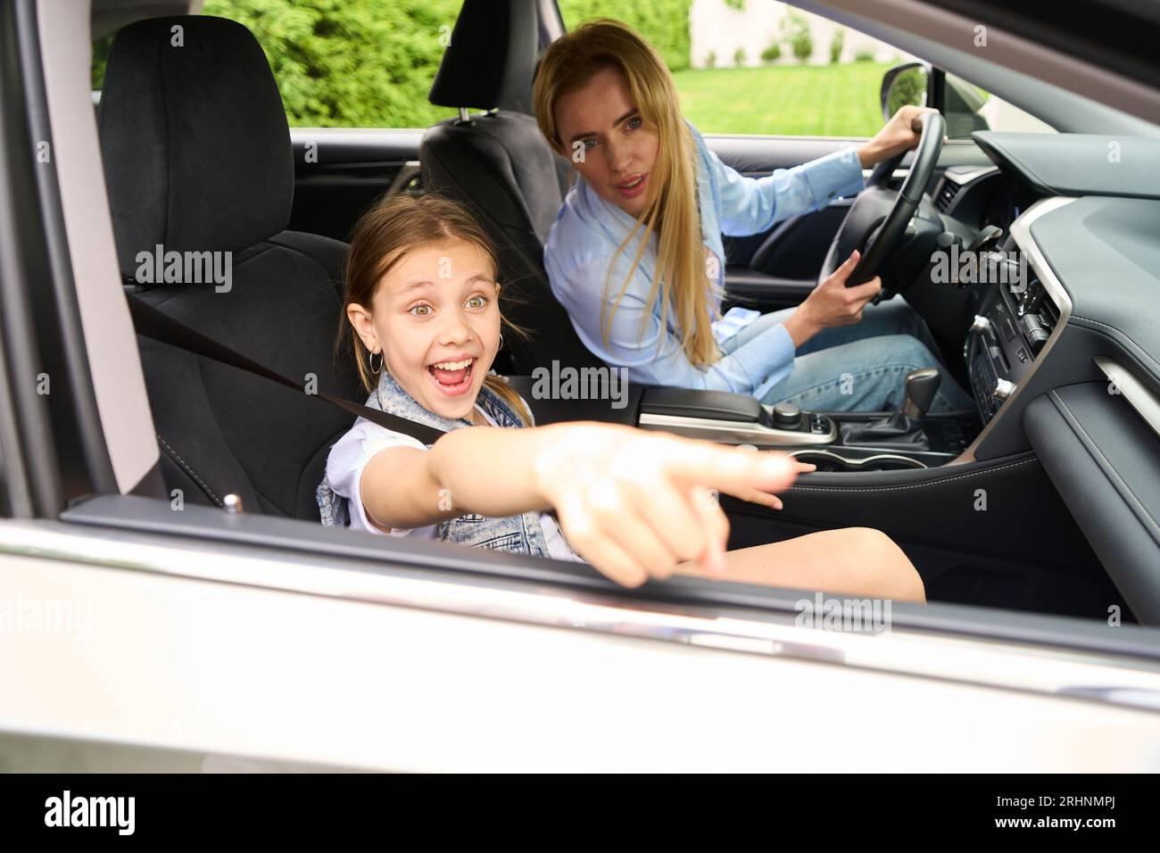 Happy little girl is pointing at something outside car window Stock ...