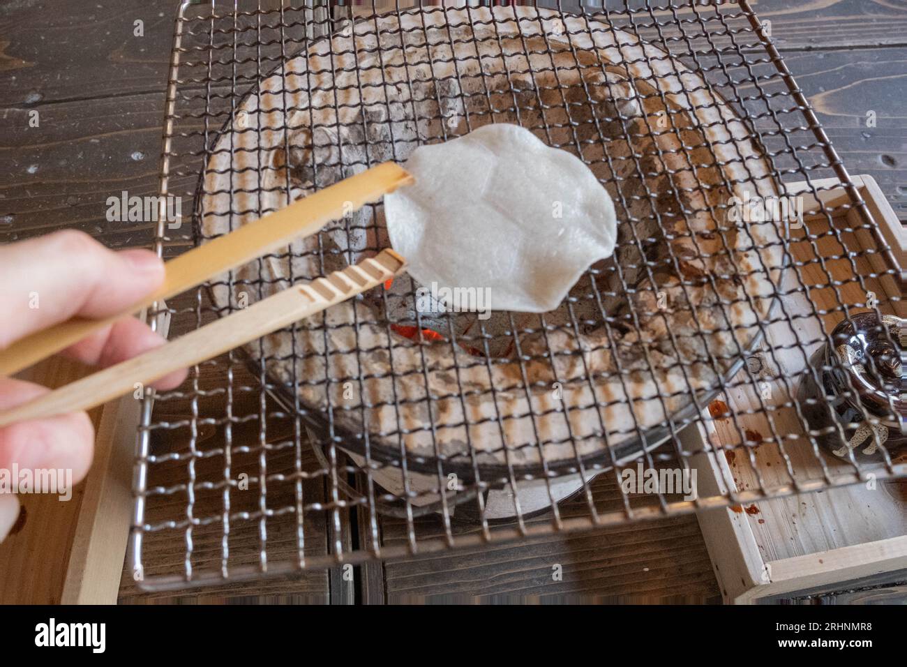 cooking "osenbei" or Japanese rice crackers over a traditional clay ...