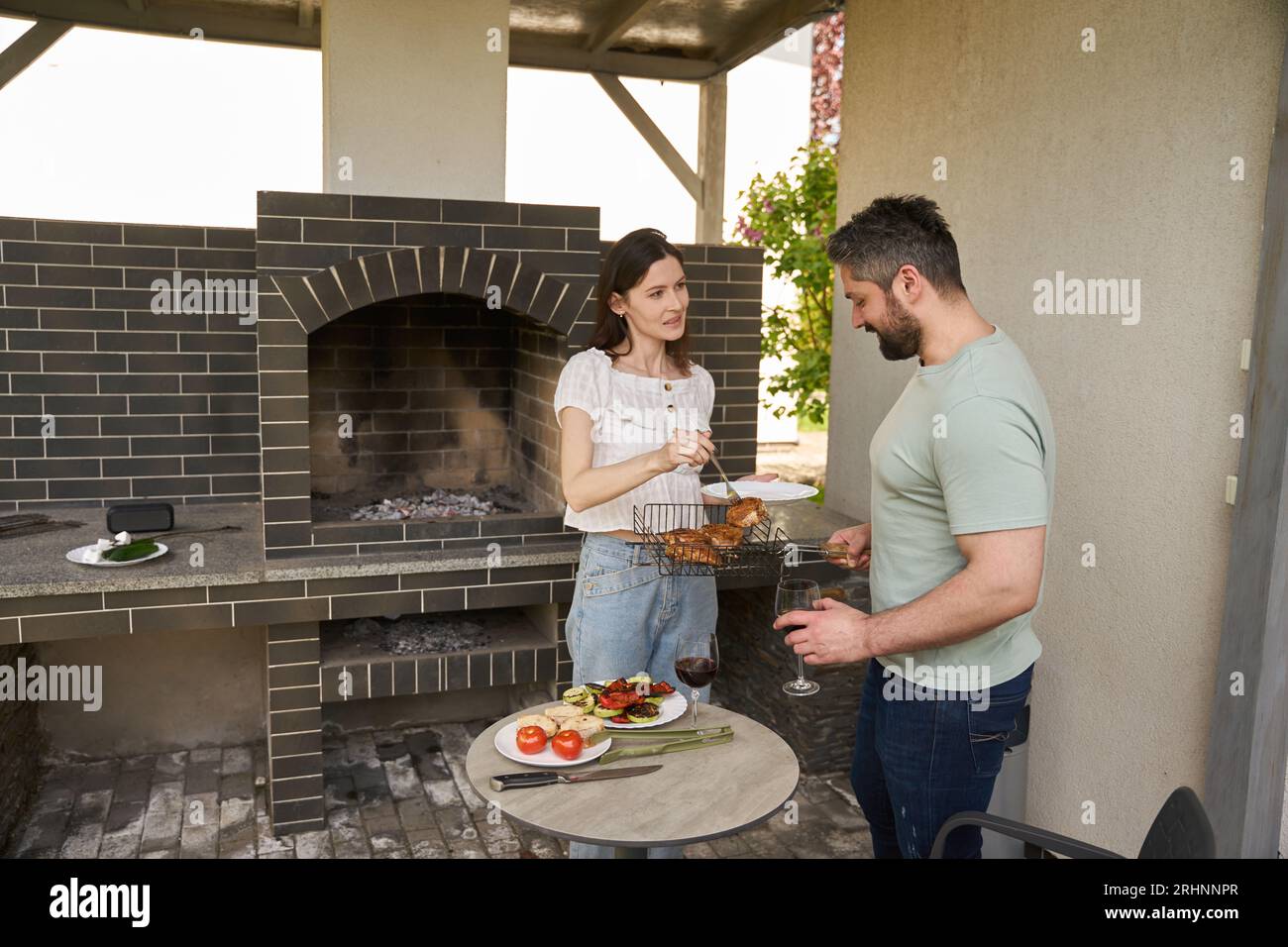 Husband and wife cook food together and chat in grill area Stock Photo ...