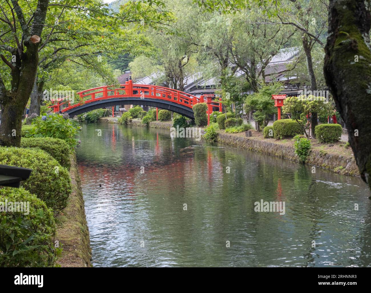 A traditional red and black wooden bridge surrounded by trees and red ...