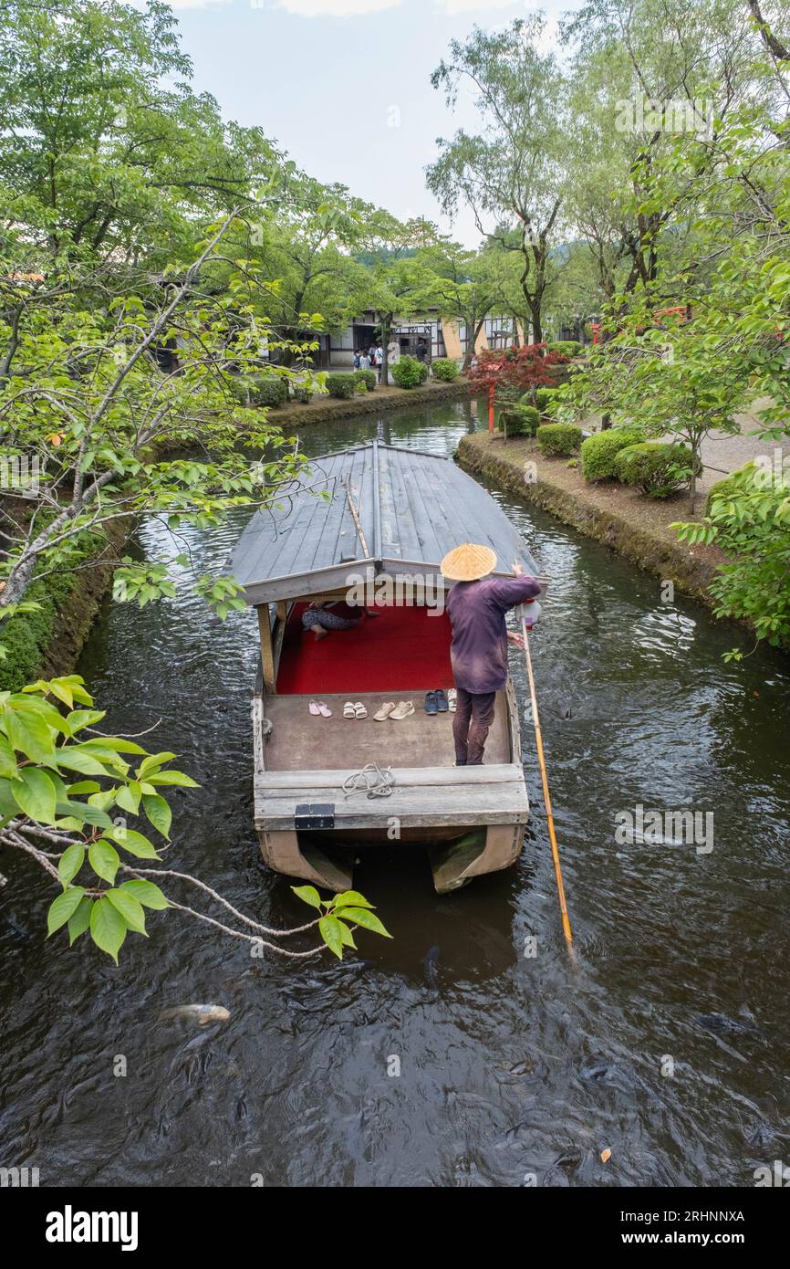 A Boatman dressed in Edo-period clothes pushing a wooden boat with a ...