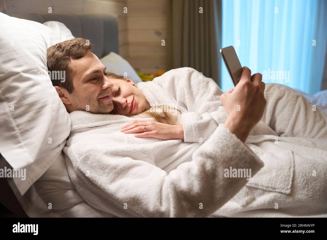 Man reading news or checking his social networks while his girlfriend resting Stock Photo - Alamy