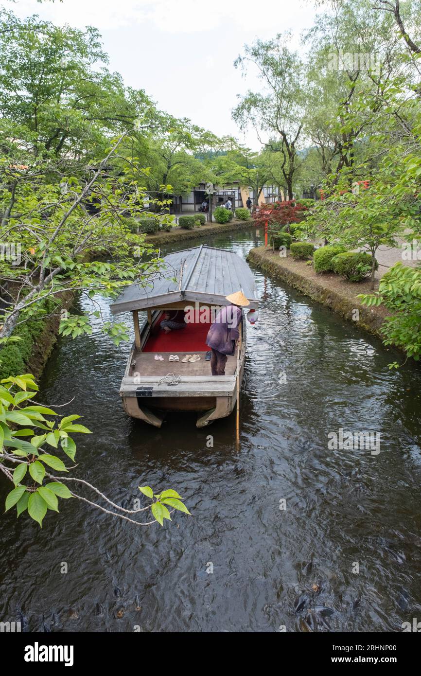 A Boatman dressed in Edo-period clothes pushing a wooden boat with a ...