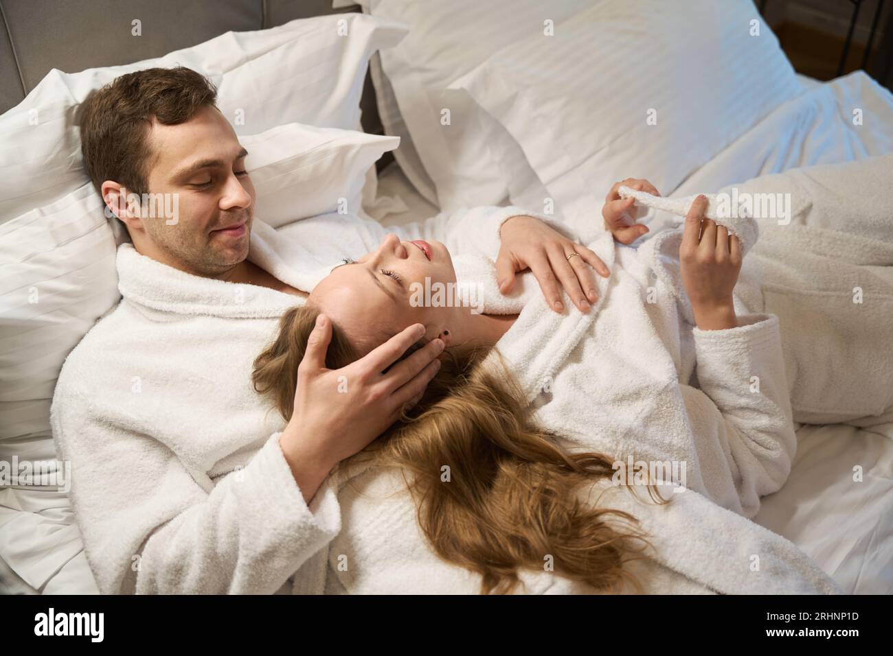 Loving man caressing hair of his beautiful wife who lying on his chest ...