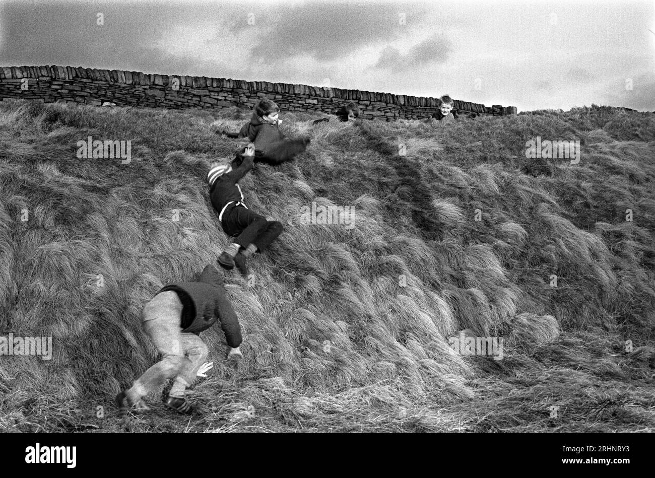 1960s children playing group of boys, friends playing rolling down a ...