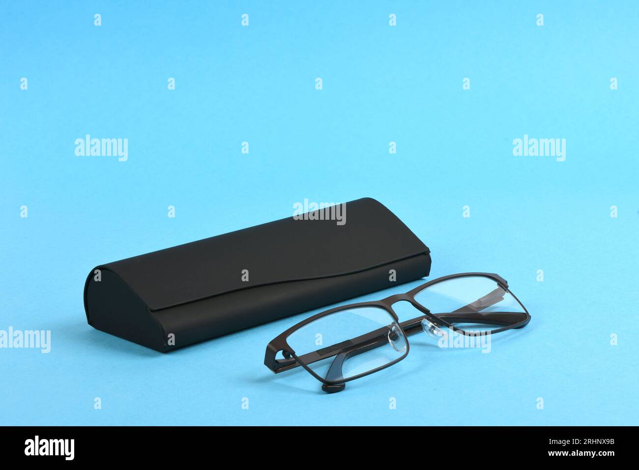 Reading glasses and black hard case isolated on blue background. High ...