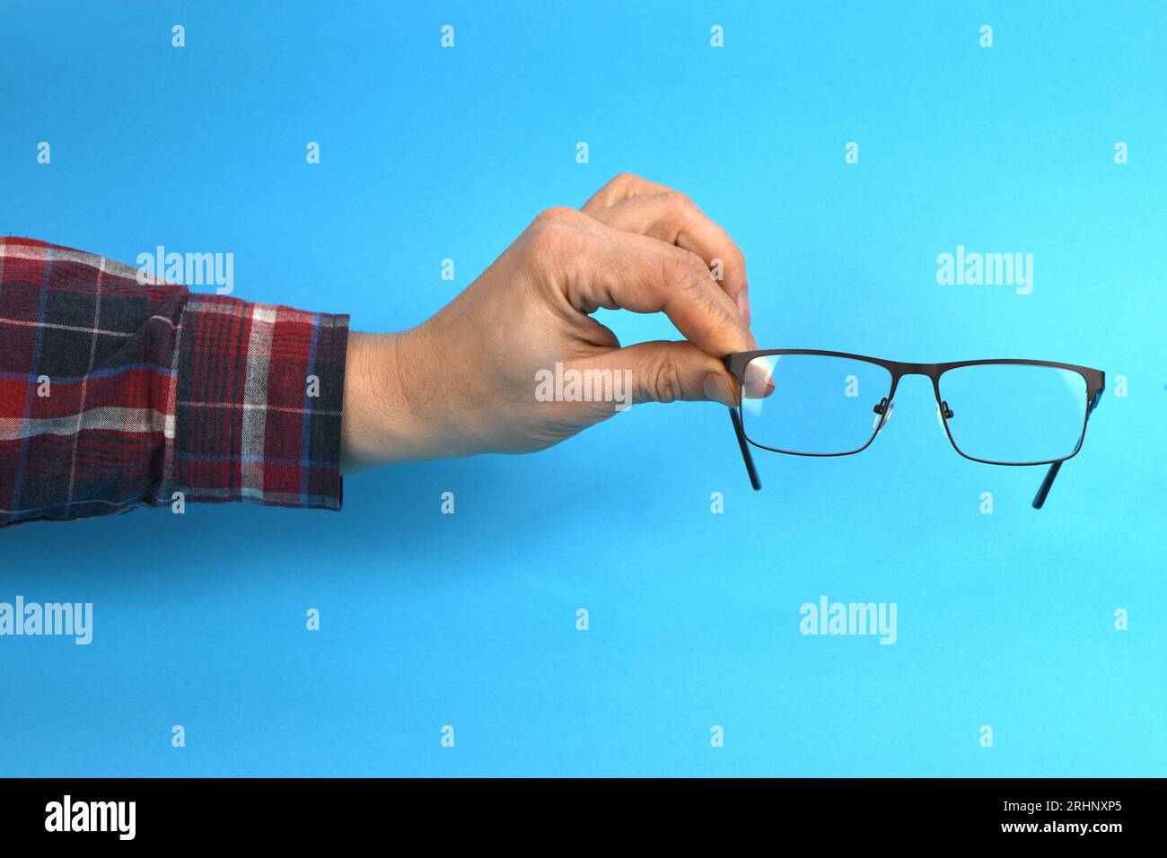 Hand holding plastic black glasses, isolated on blue background. High ...