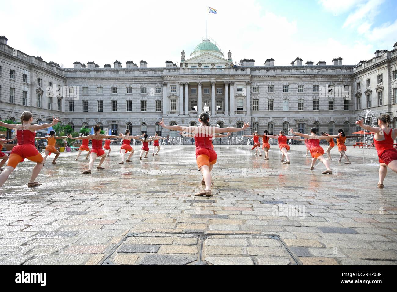22 all-female dancers in vivid orange costumes designed by Ursula ...