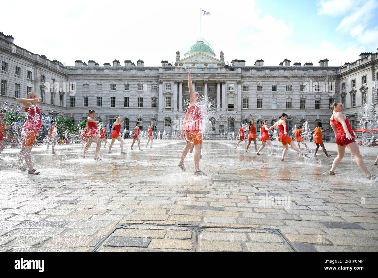 22 all-female dancers in vivid orange costumes designed by Ursula ...