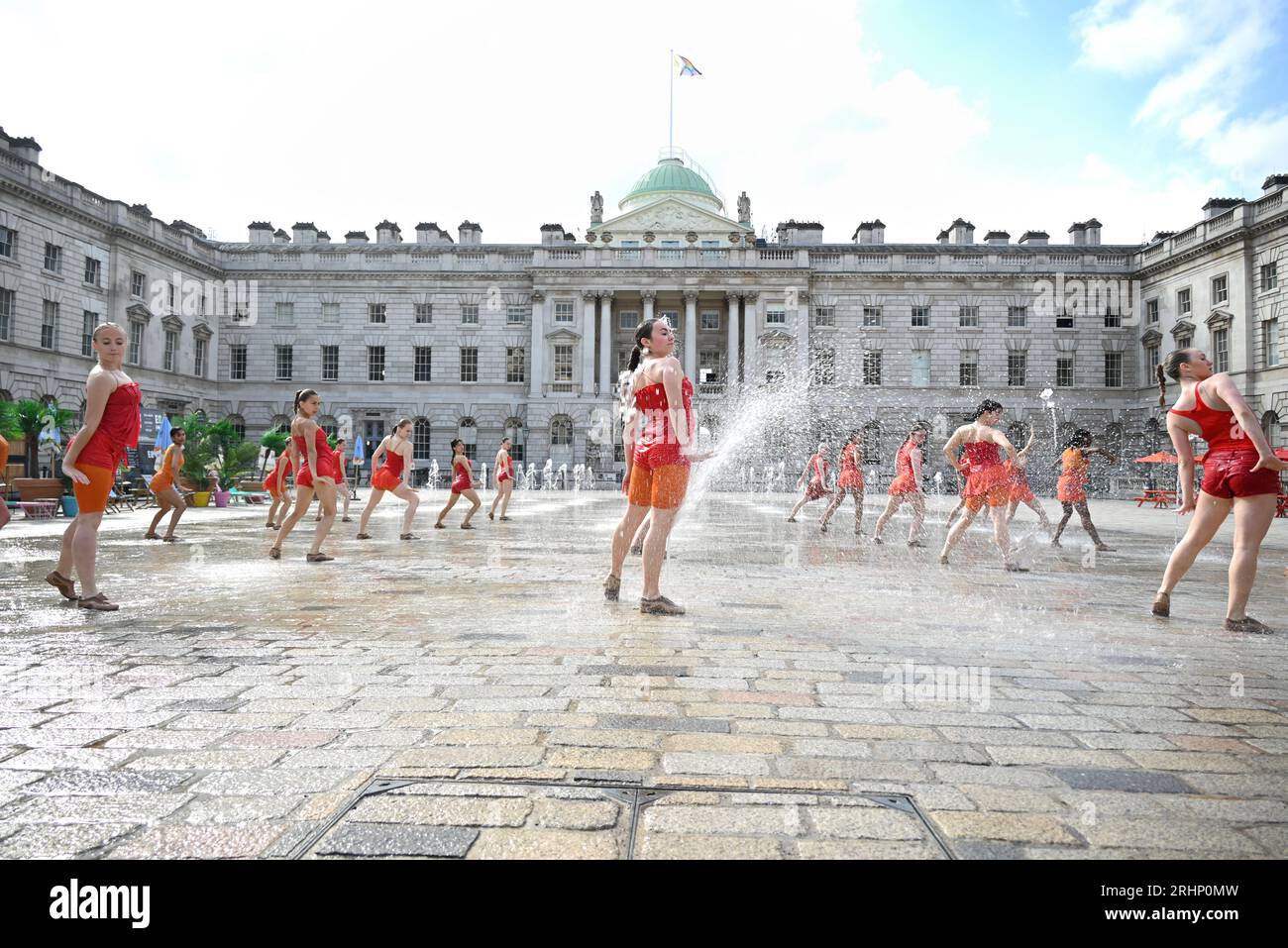 22 all-female dancers in vivid orange costumes designed by Ursula ...