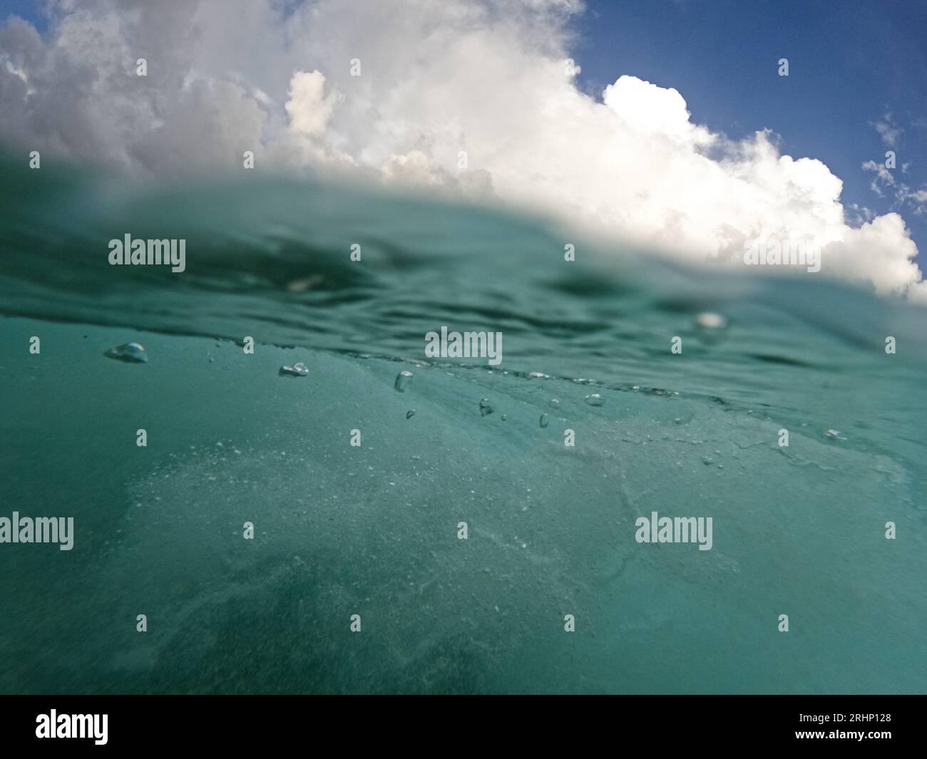 Vibrant turquoise ocean and white clouds. Underwater view and above ...