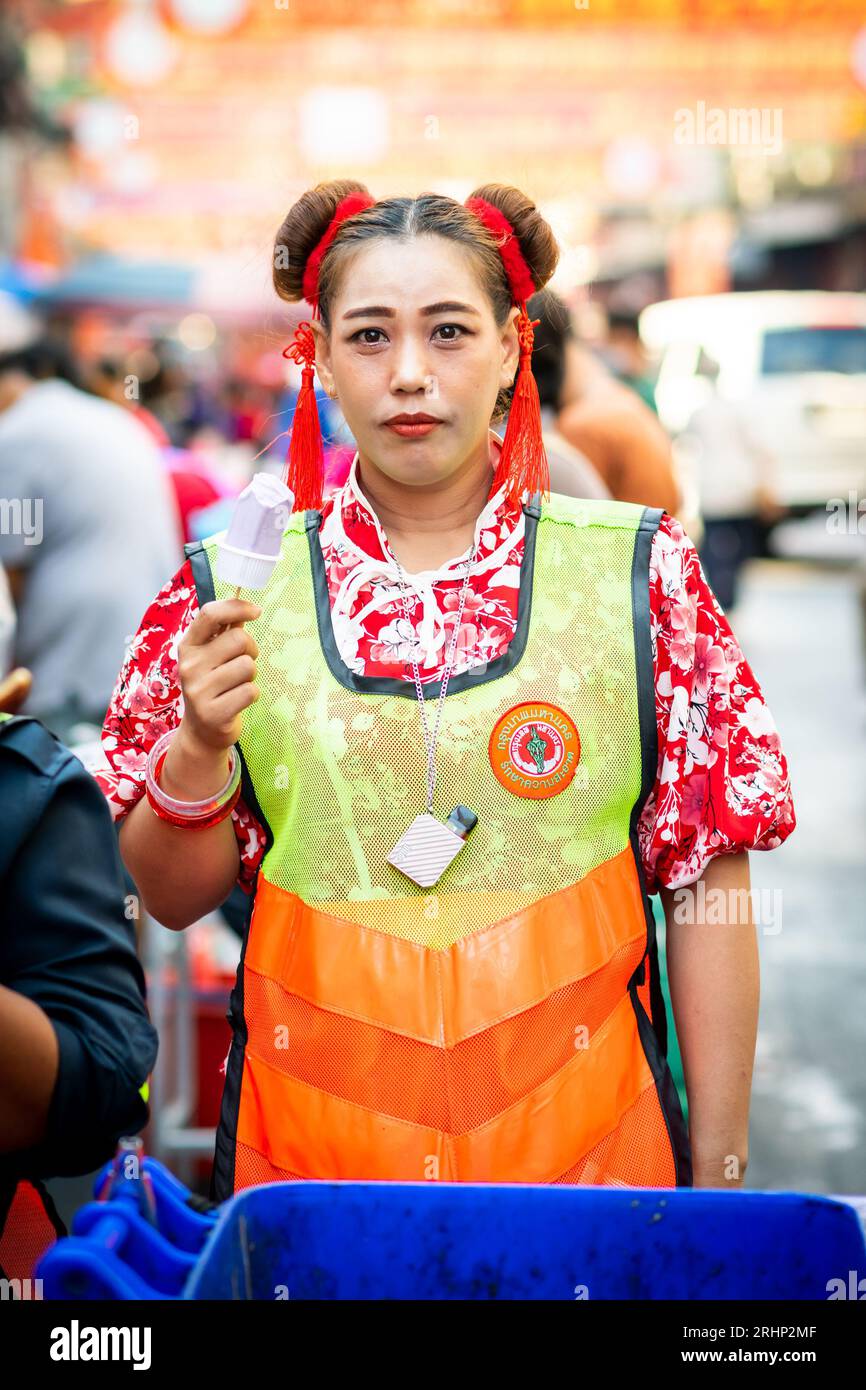A Thai road sweeper enjoys an ice cream on her break on Yaowarat Rd ...