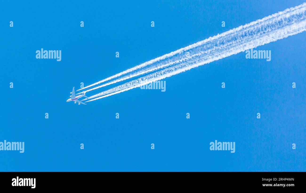 Four engined airplane during flight with condensation trails Stock ...