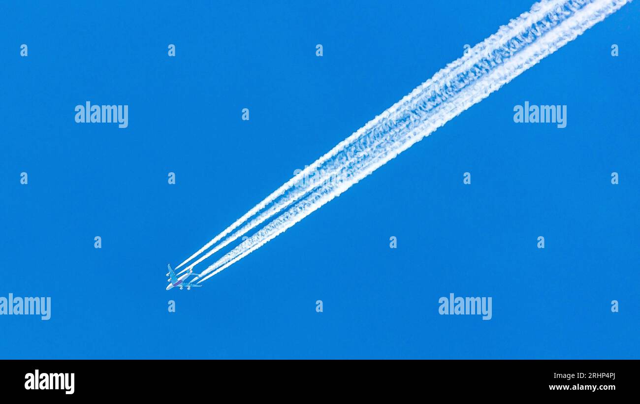 Four engined airplane during flight with condensation trails Stock ...