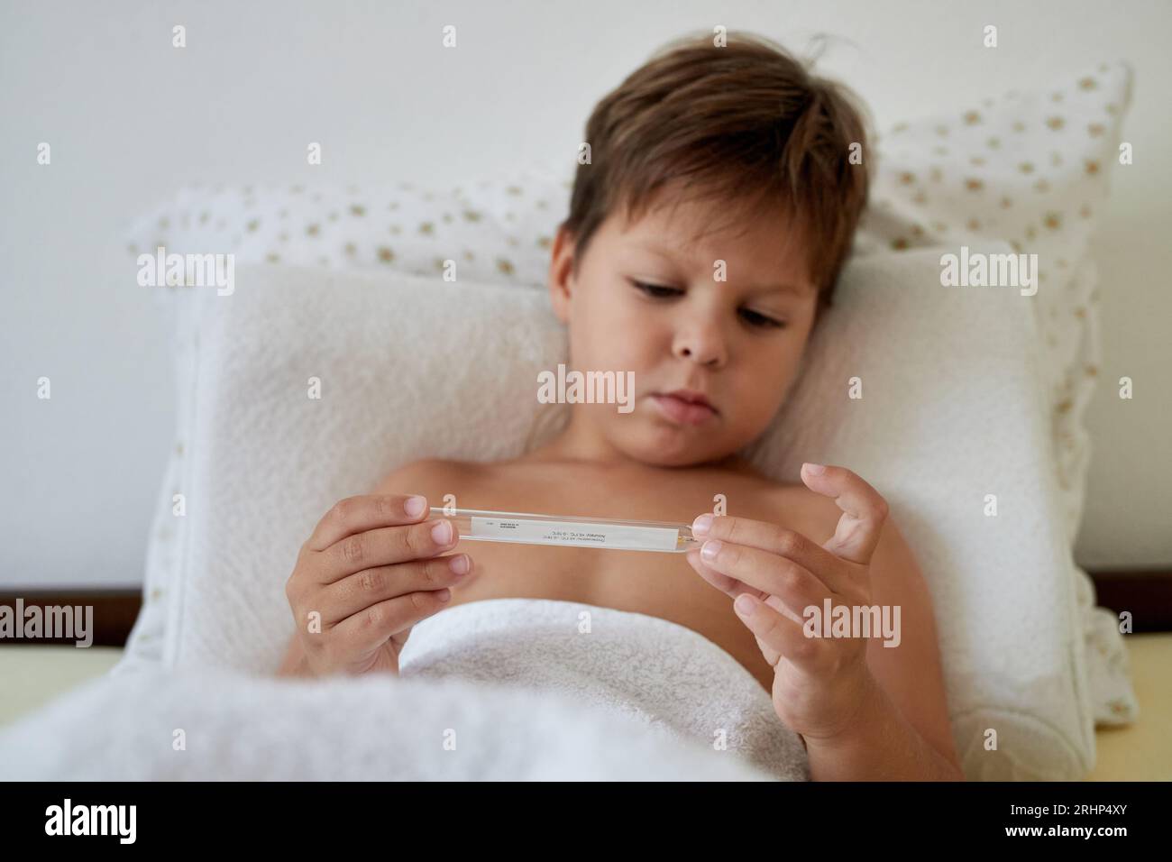 A sick child lies in bed and looks at a mercury thermometer. Heat Stock ...