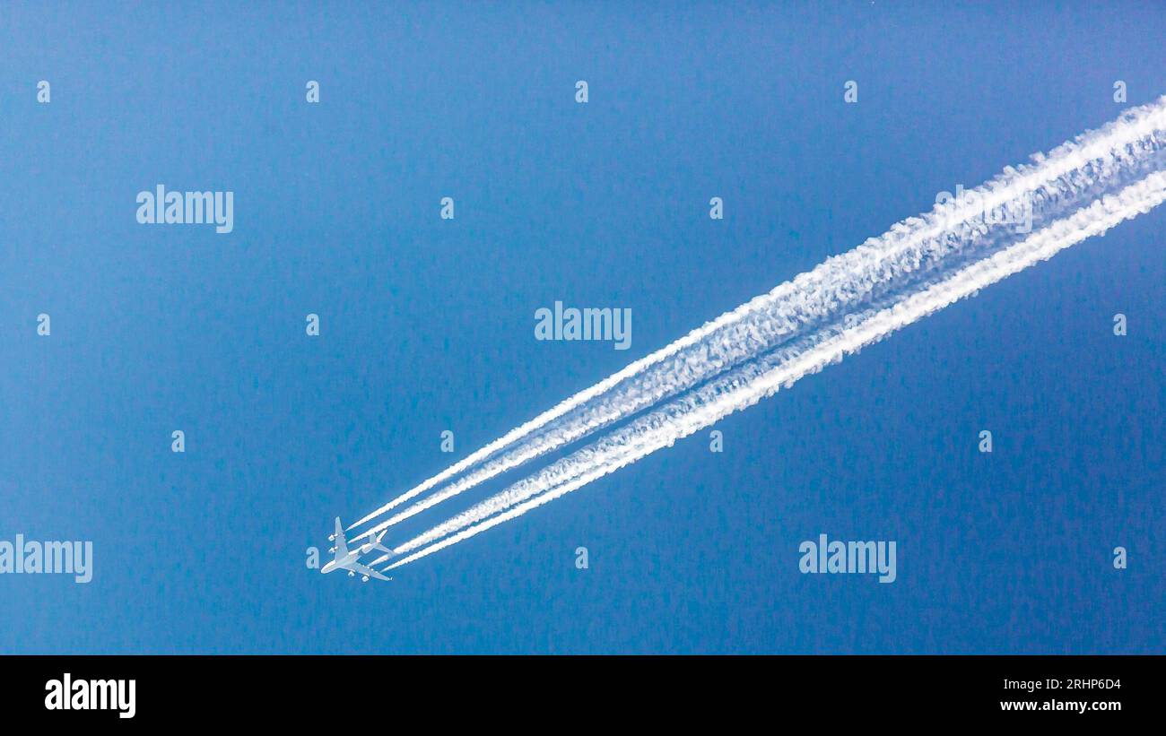 Four engined airplane during flight with condensation trails Stock ...