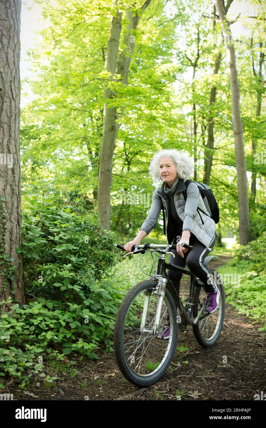 Elderly woman riding bicycle Stock Photo - Alamy