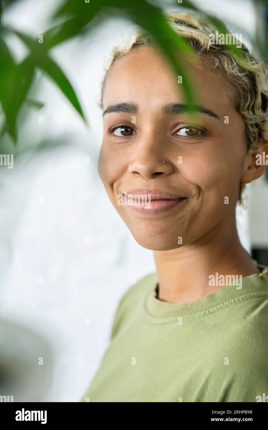 Woman looking through green plant Stock Photo - Alamy