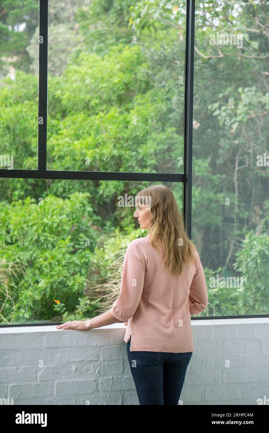 Woman looking through window Stock Photo - Alamy