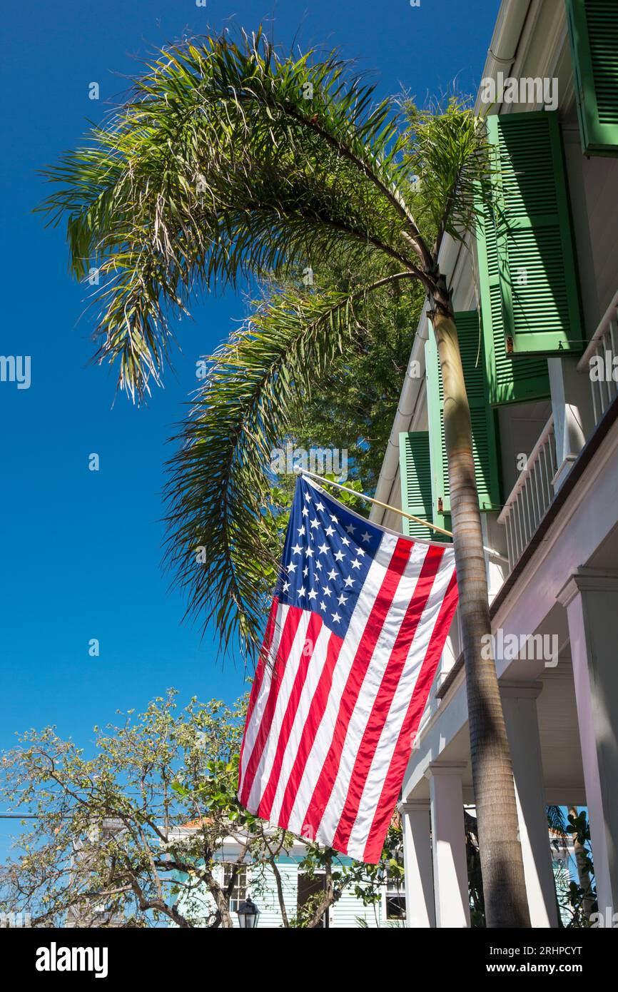 Key West, Florida, USA. US flag flying beneath palm tree from balcony ...