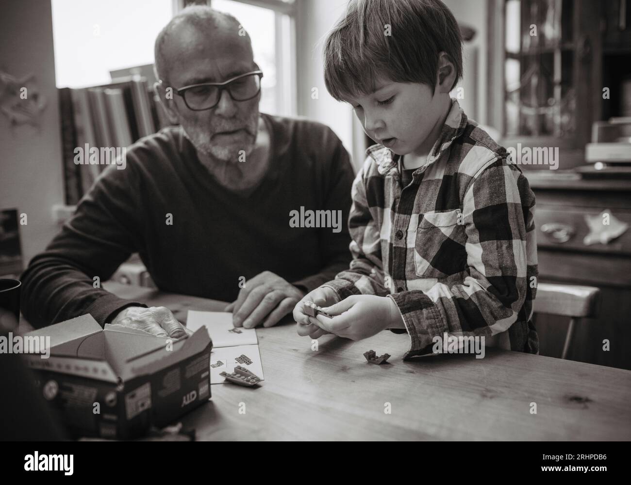 Boy tinkering with his grandfather at dining table Stock Photo - Alamy