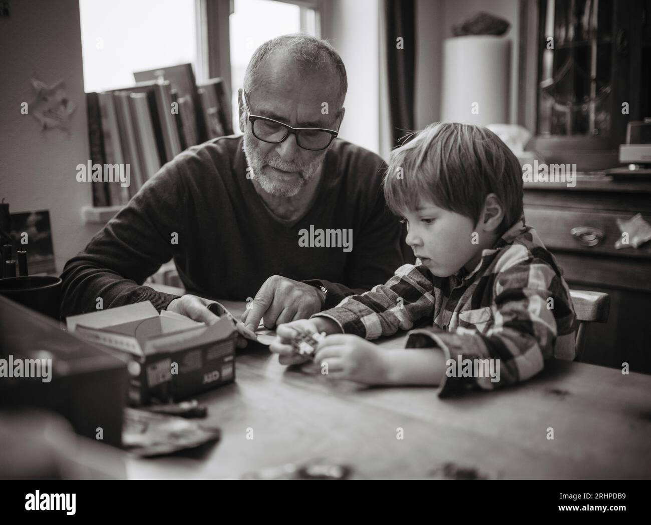 Boy tinkering with his grandfather at dining table Stock Photo - Alamy