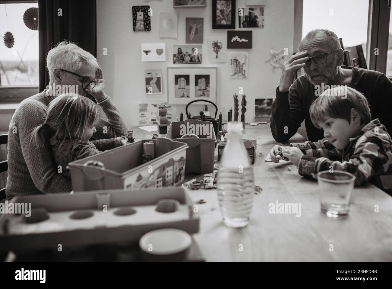 Grandparents play together with their grandchildren at the dining table ...