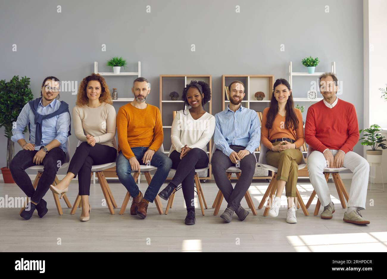 Happy diverse audience sitting on row of chairs during event in modern ...