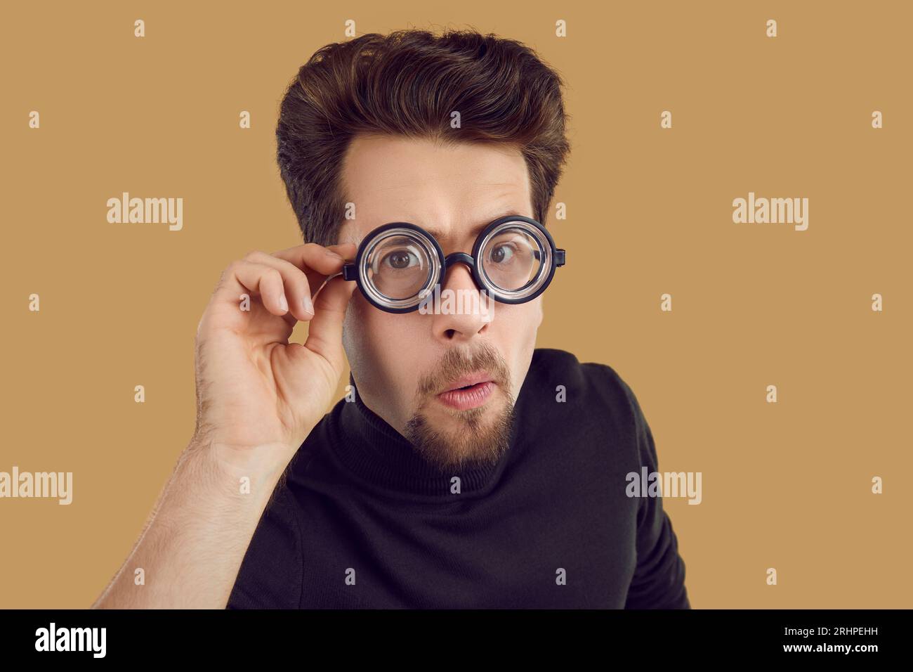 Portrait of funny alert and curious man looking at you through glasses ...