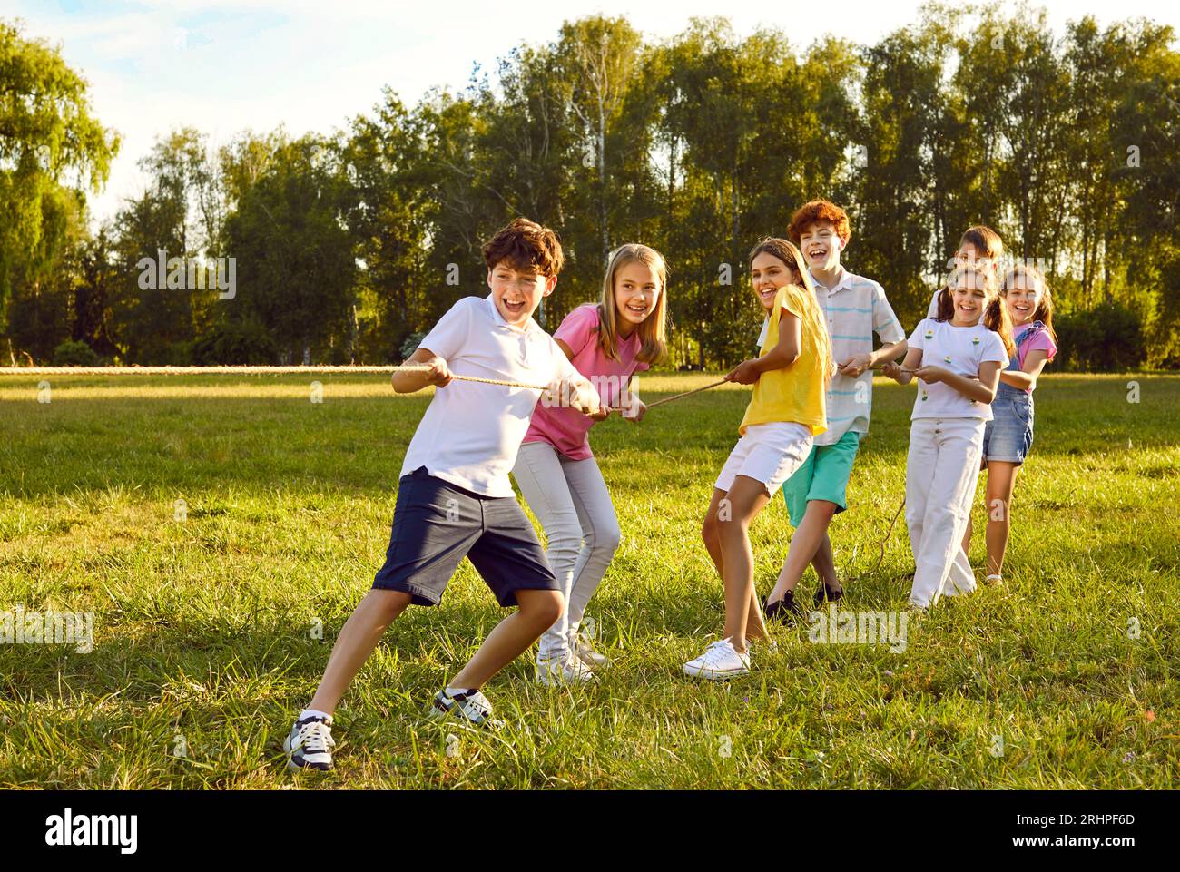 Group of happy kids having fun and playing tug of war in summer camp on ...