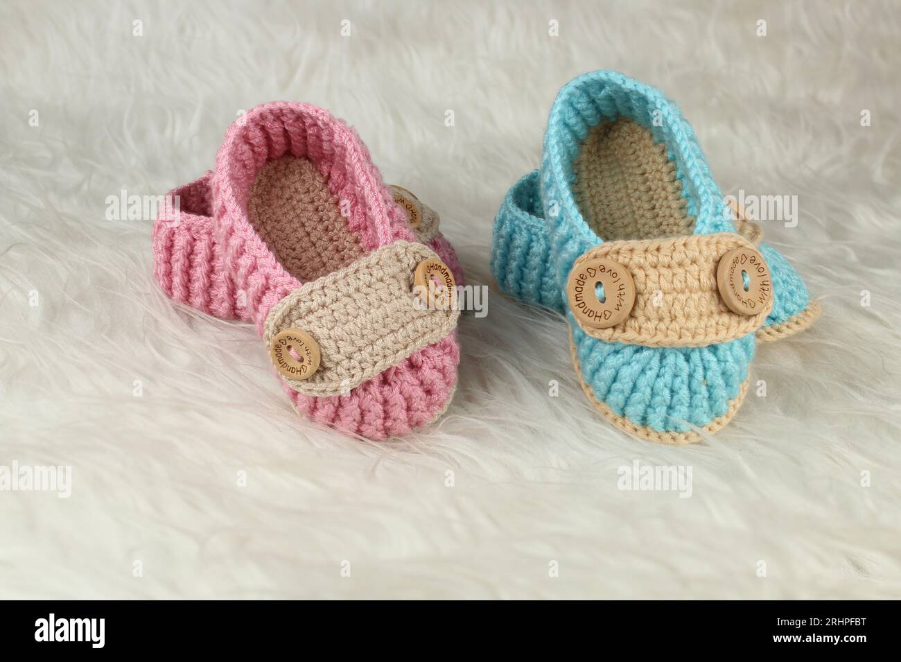Knitted pink and blue booties on white fluffy blanket. Gender party ...