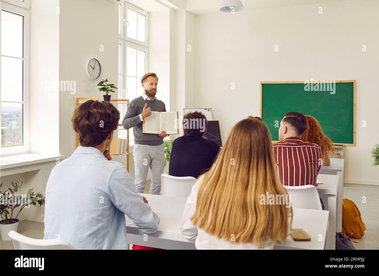 Male teacher in modern classroom conducts interesting lecture for ...